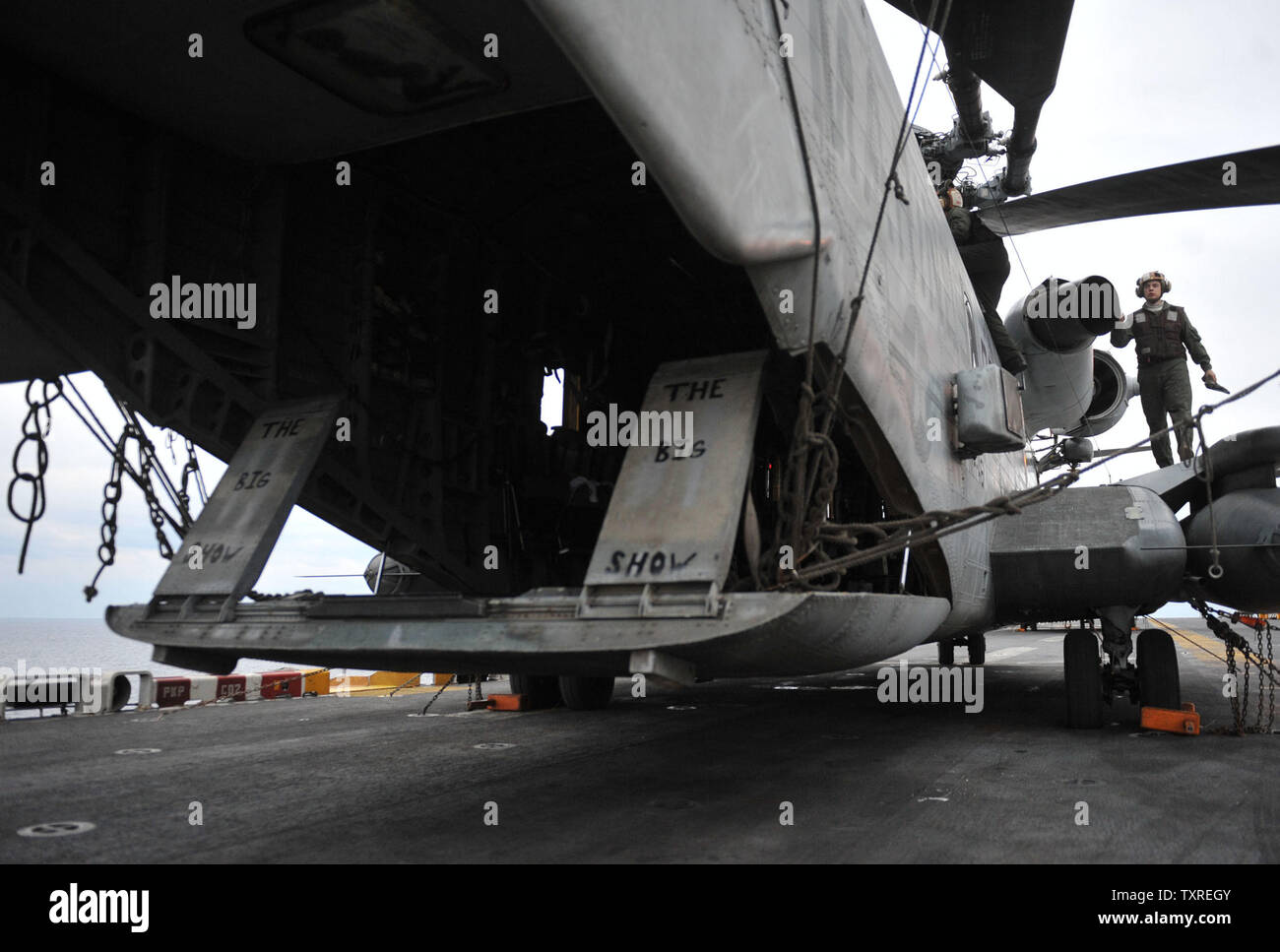 A naval aircraft handler works on a Marine CH-53e helicopter on the ...