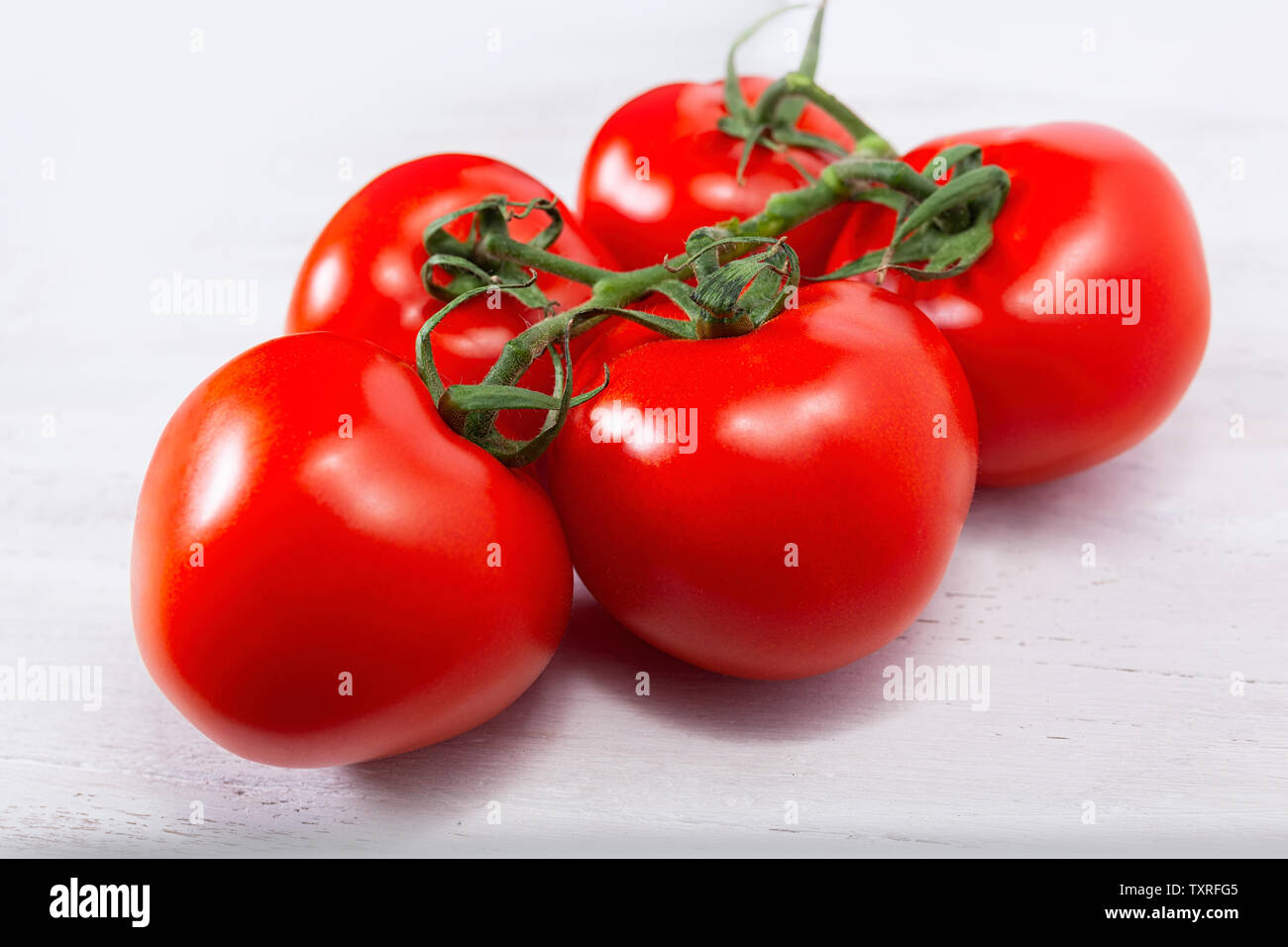 Group of five fresh, ripe red tomatoes, still connected through the ...