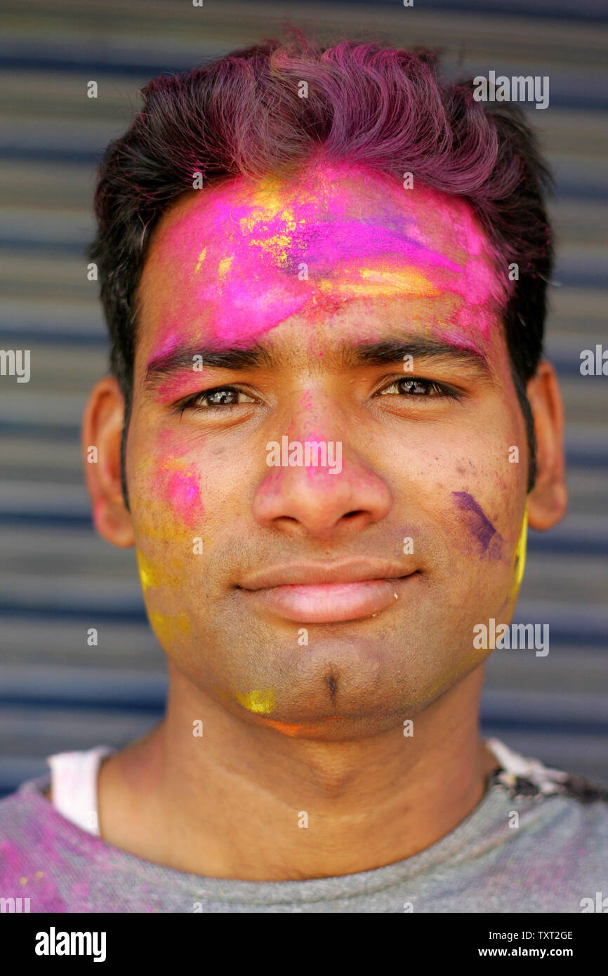 An Indian man with a face smeared with colored powder poses for a ...