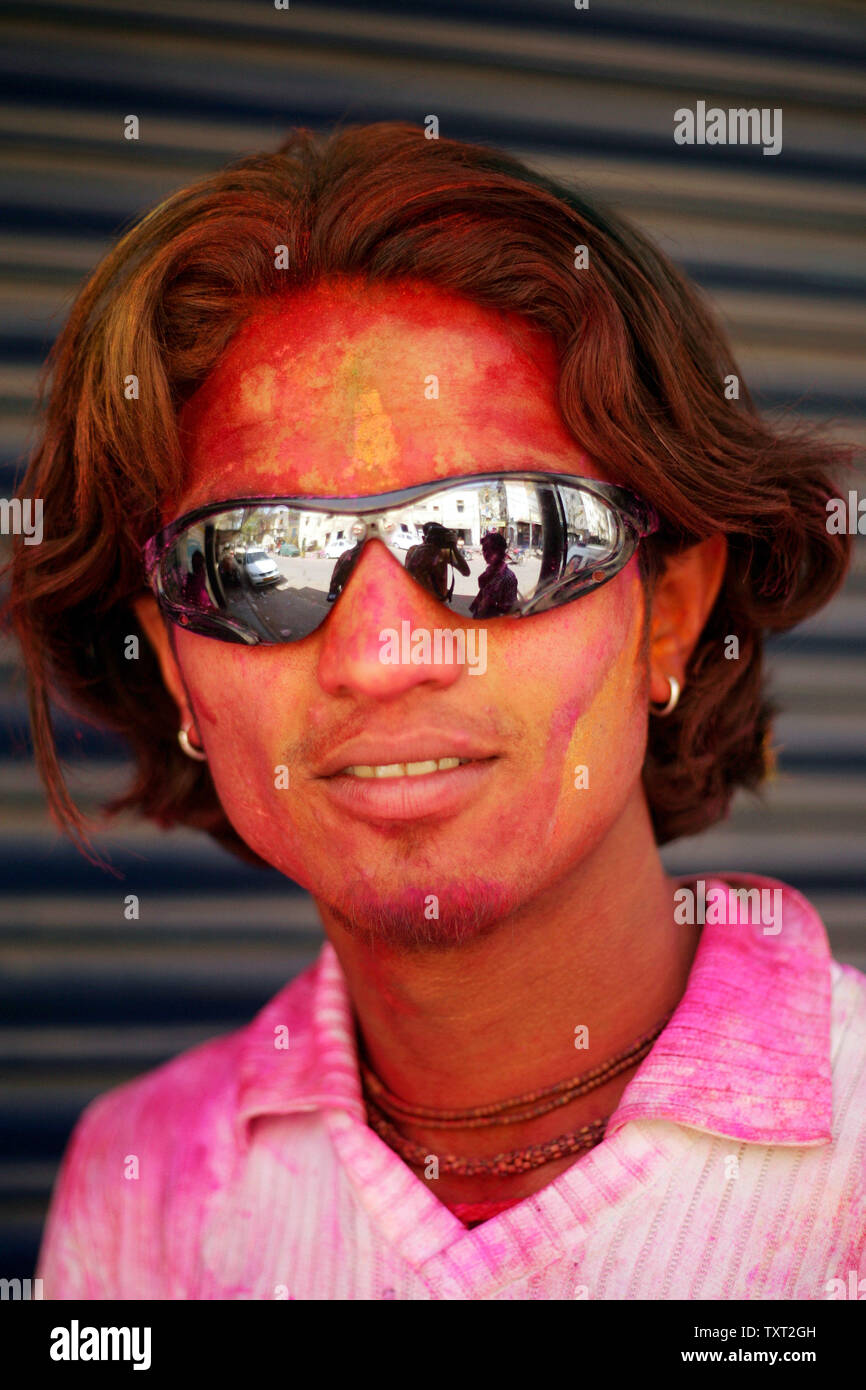 An Indian man with a face smeared with colored powder poses for a ...