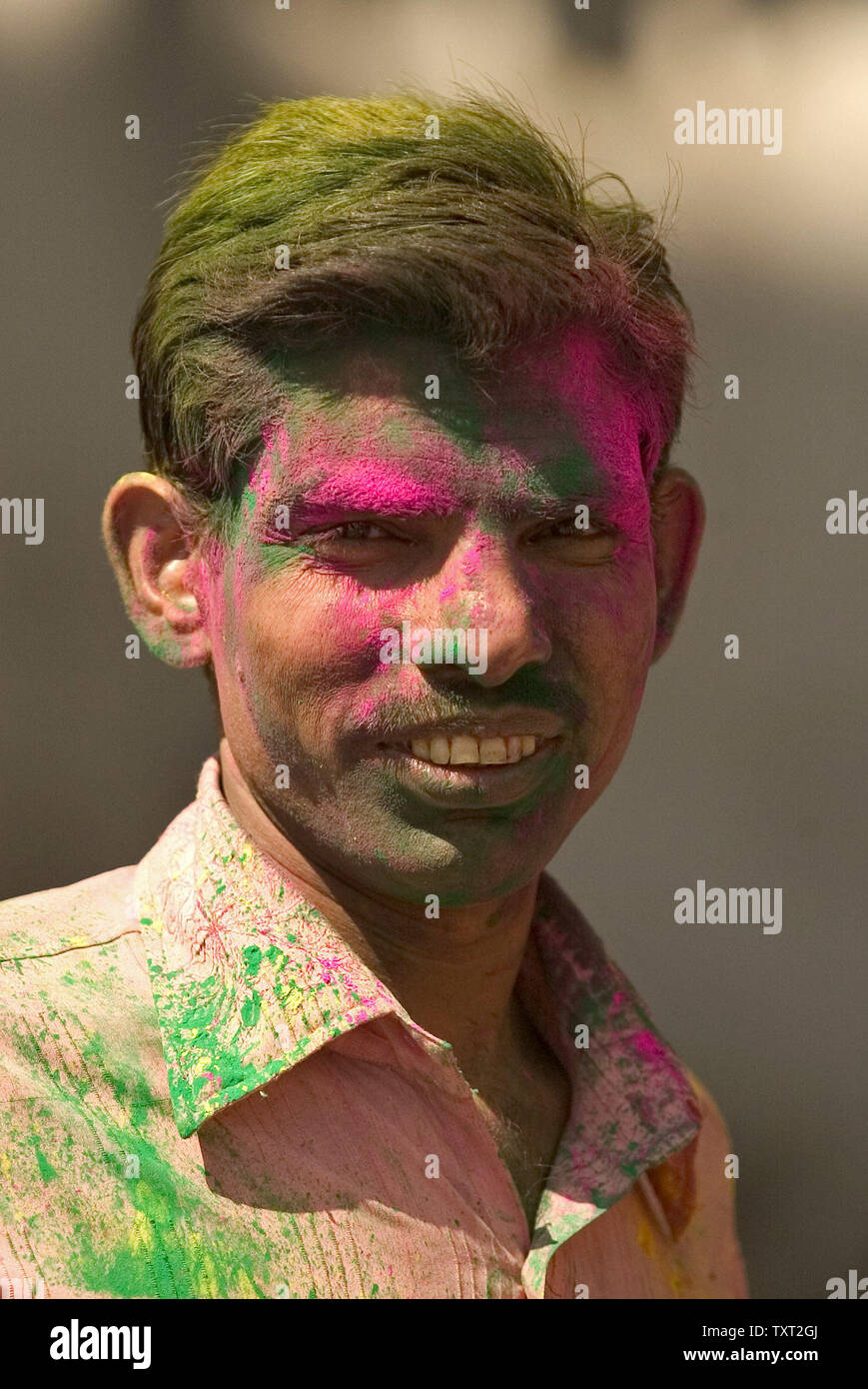 An Indian man with a face smeared with colored powder poses for a ...