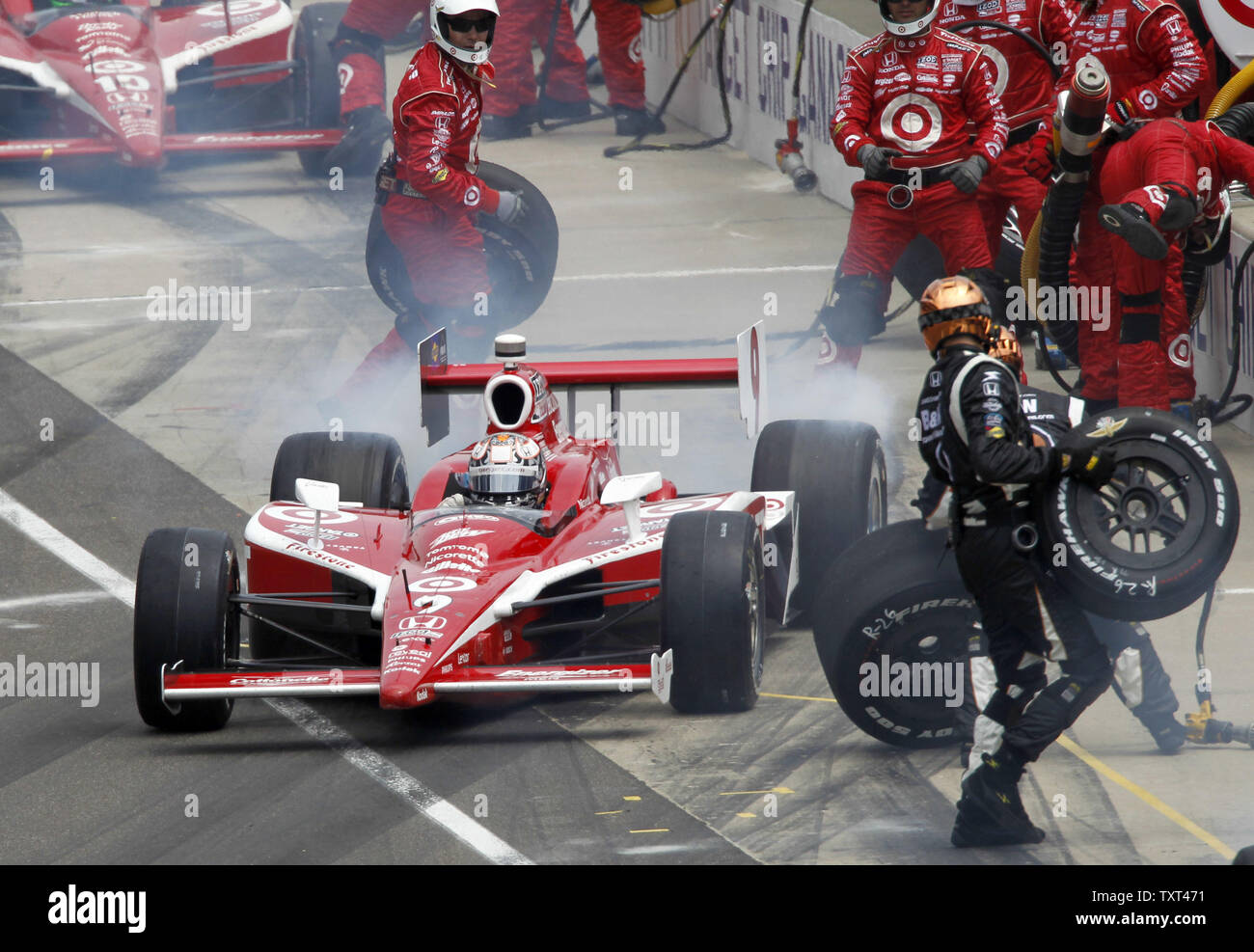 Scott Dixon dodges a member of Alex Tagliani's crew as he leaves the ...