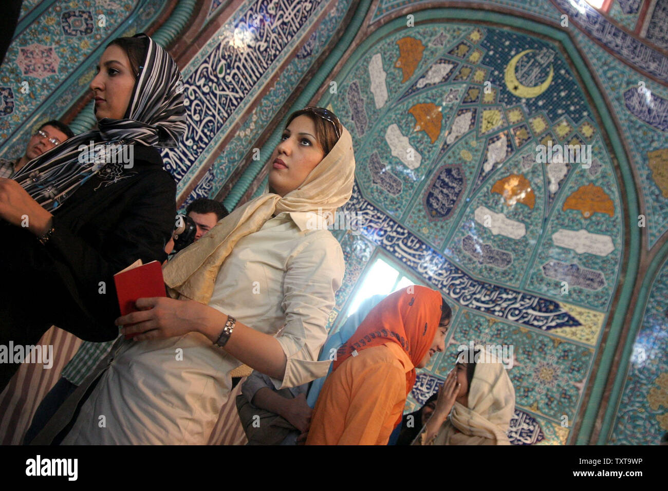Iranian voters hold their ID cards as they queue inside the Ershad ...