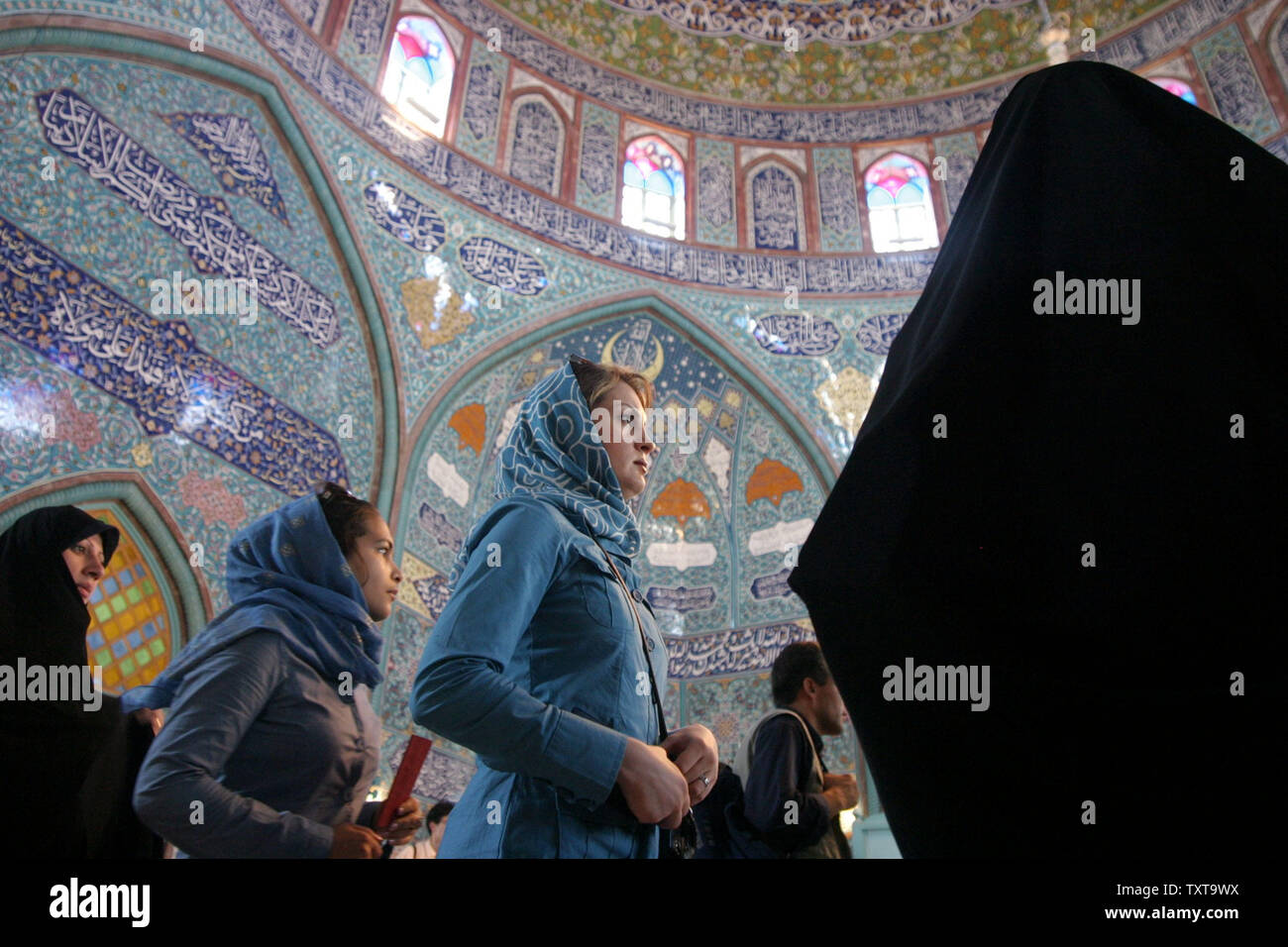 Iranian voters hold their ID cards as they queue inside the Ershad ...