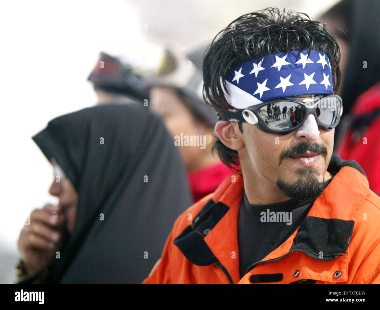 Iranian skier wears a USA headband in front of a woman in traditional ...