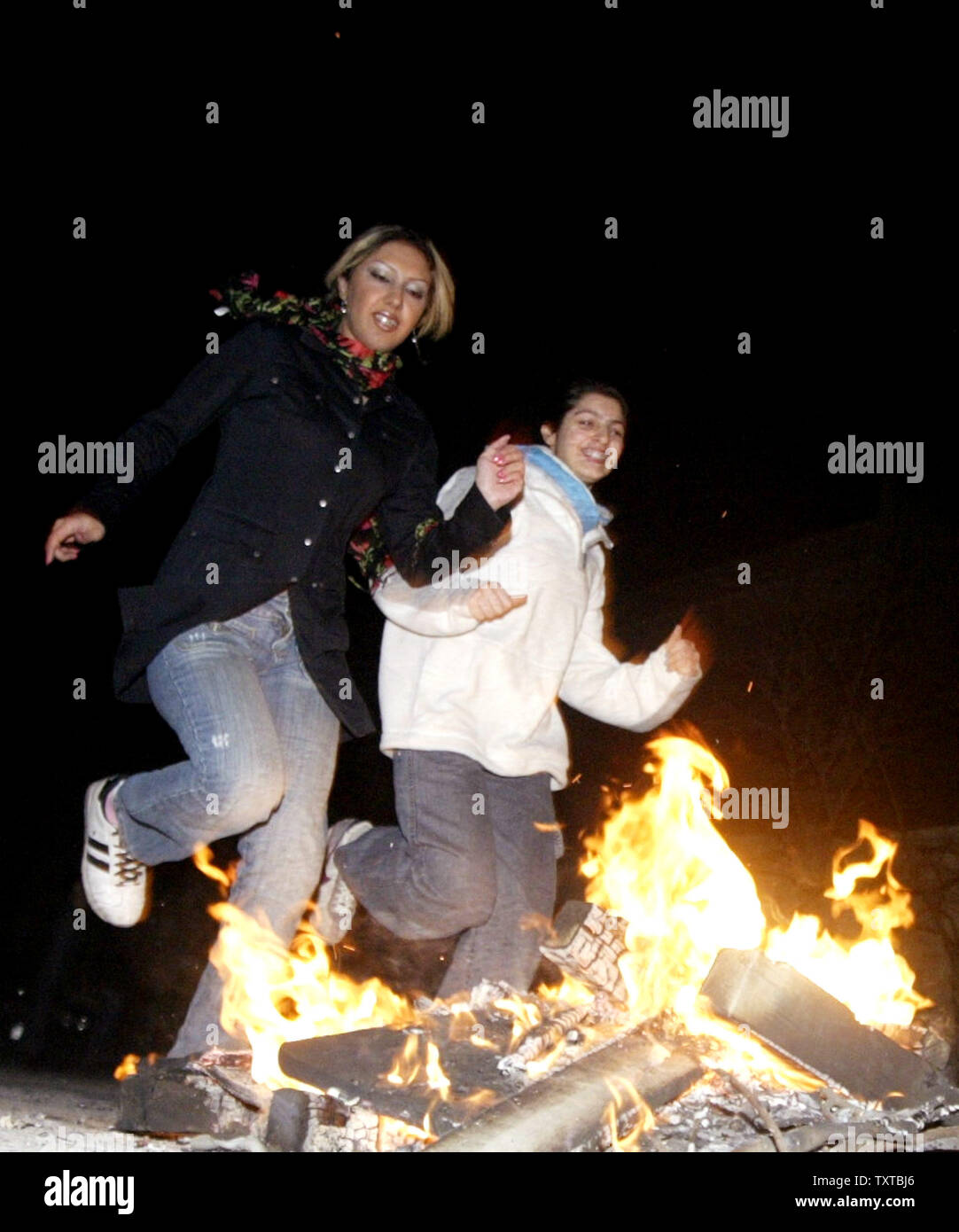 Iranian young women jump over a fire during a ceremony celebrating the ...