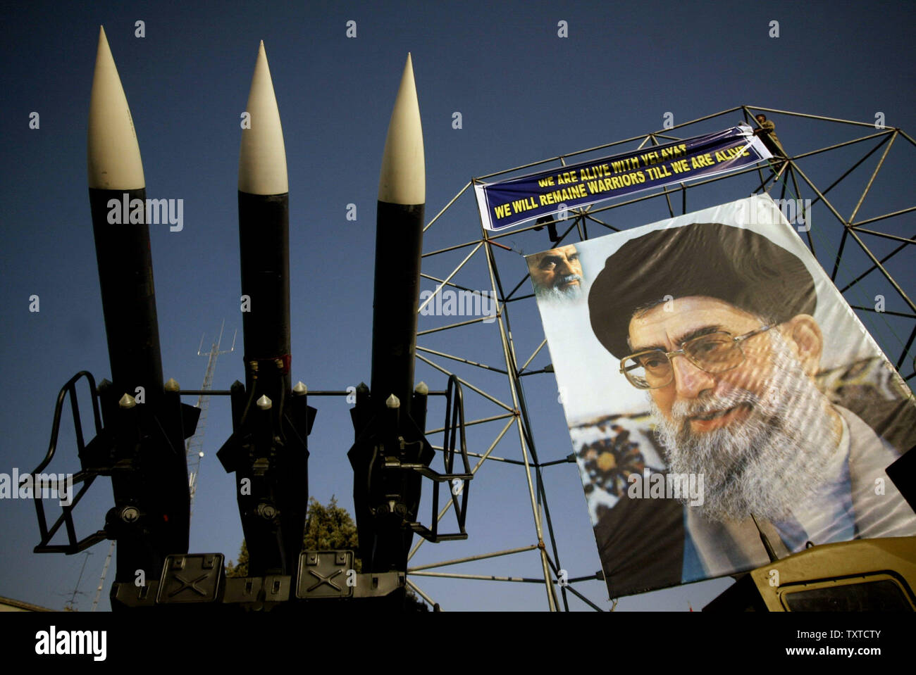 Two workers adjust a placard above a big picture of Iran's supreme ...