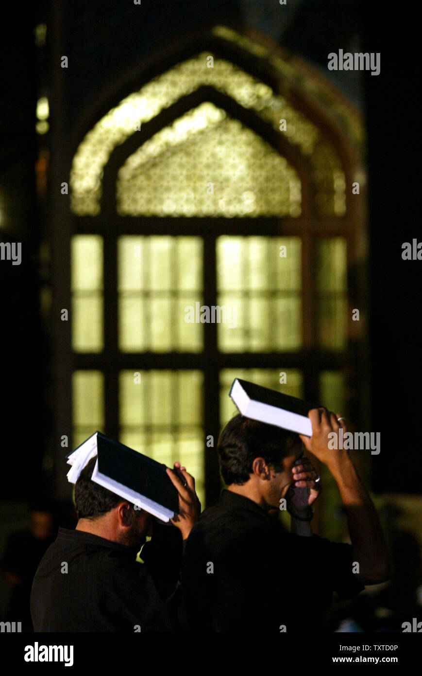 Muslims hold copies of the Koran on their heads as they pray and mourn ...