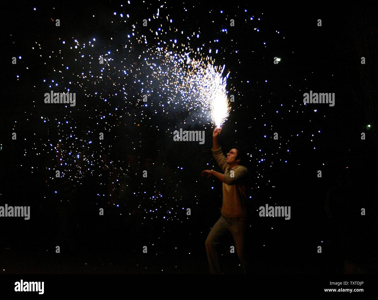 An Iranian young man throws a firecracker during a ceremony celebrating ...