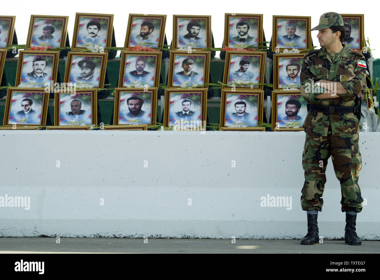 An Iranian army soldier stands guard in front of photos of Iranian ...