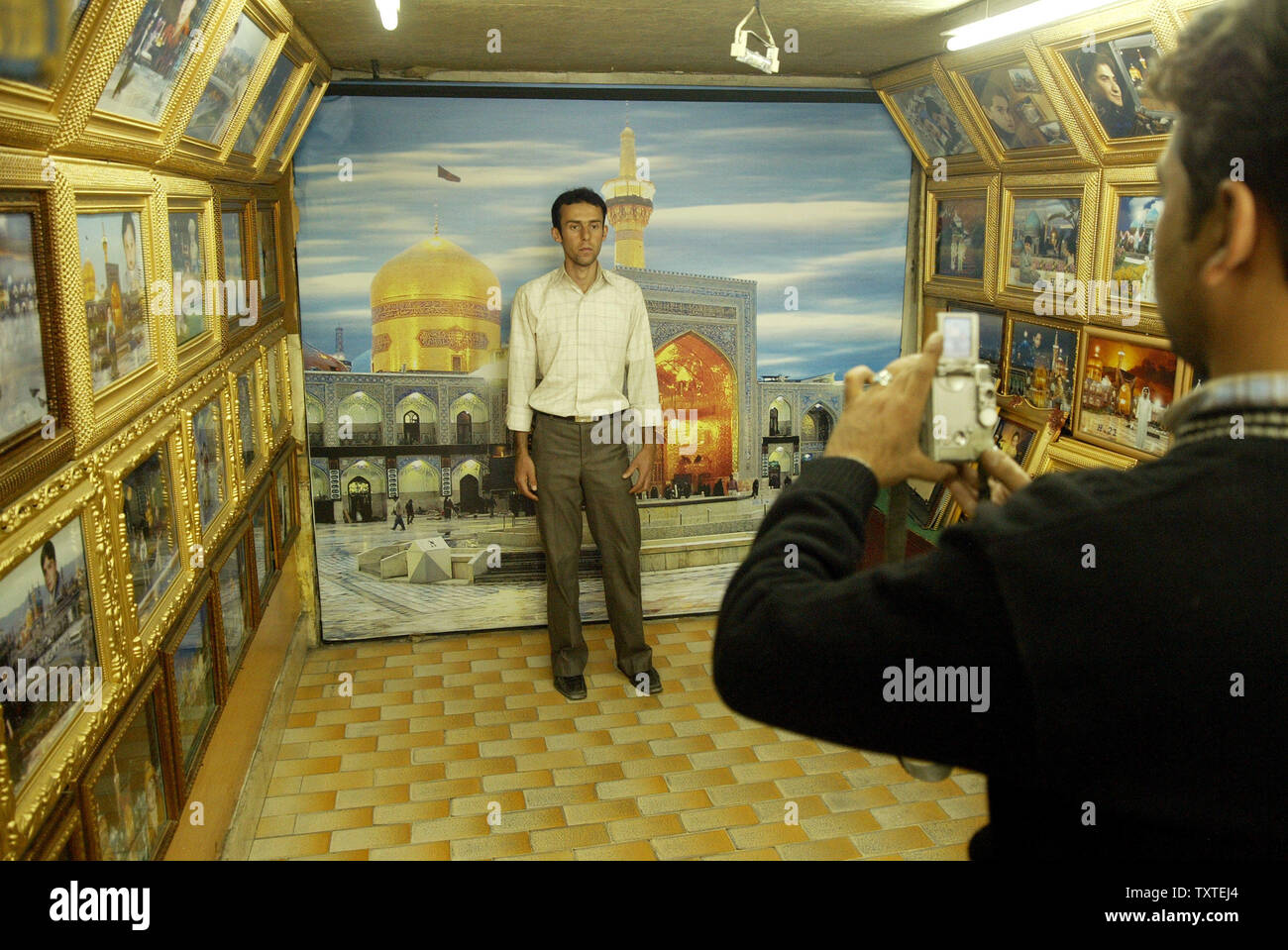 An Iranian man poses for a local photographer in front of a backdrop of ...