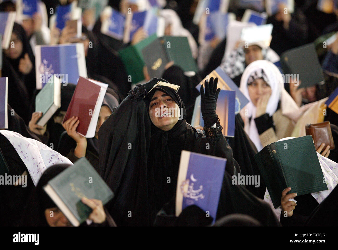 Iranian Muslims pilgrims hold copies of the Koran as they mourn and ...