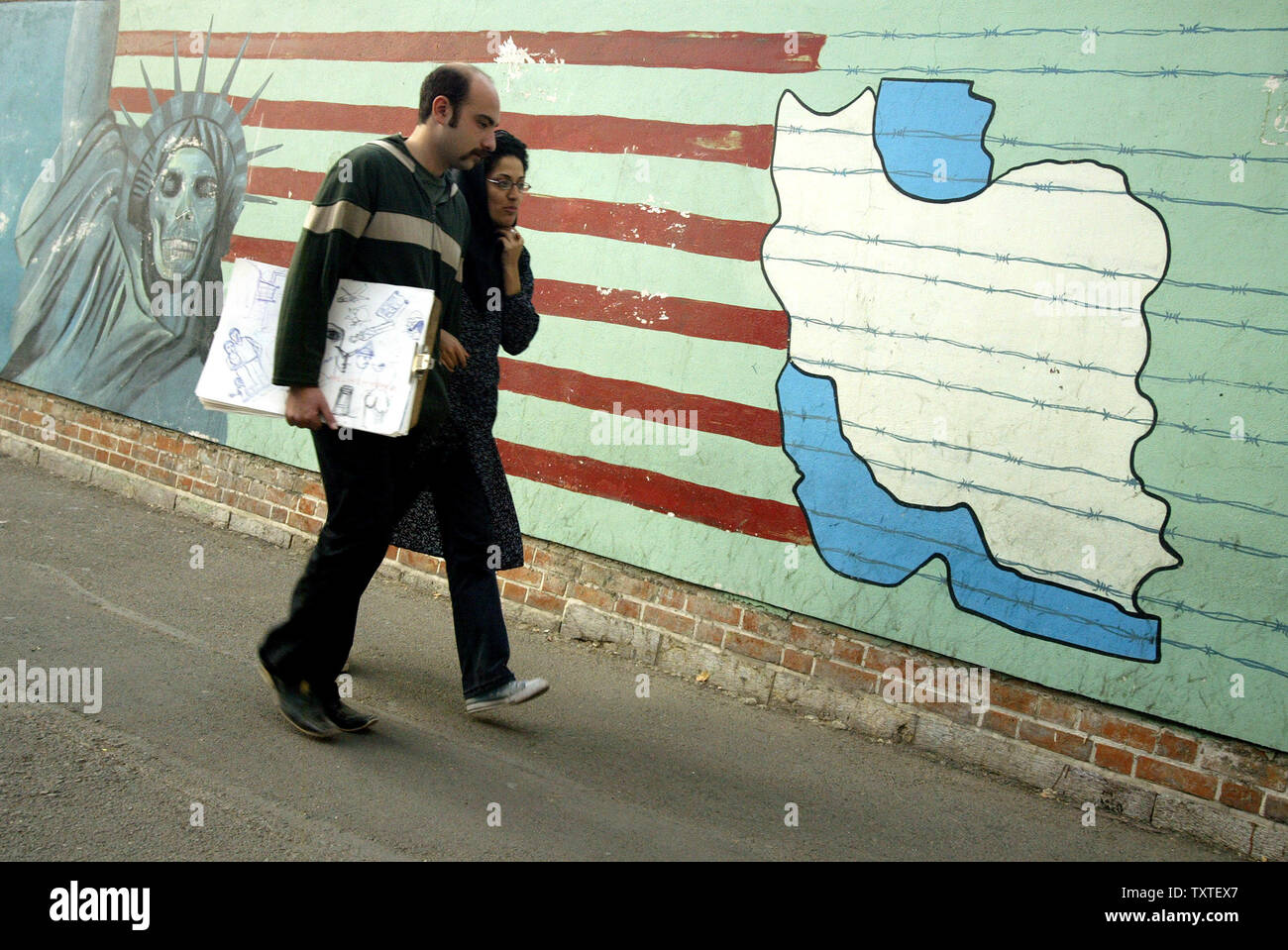 An Iranian couple pass in front of graffiti art characterizing the U.S ...