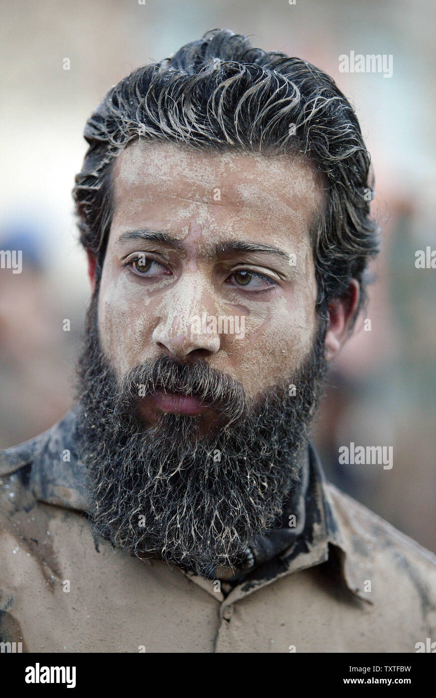 An Iranian Shiite Muslim man covered in mud, takes part in a ...