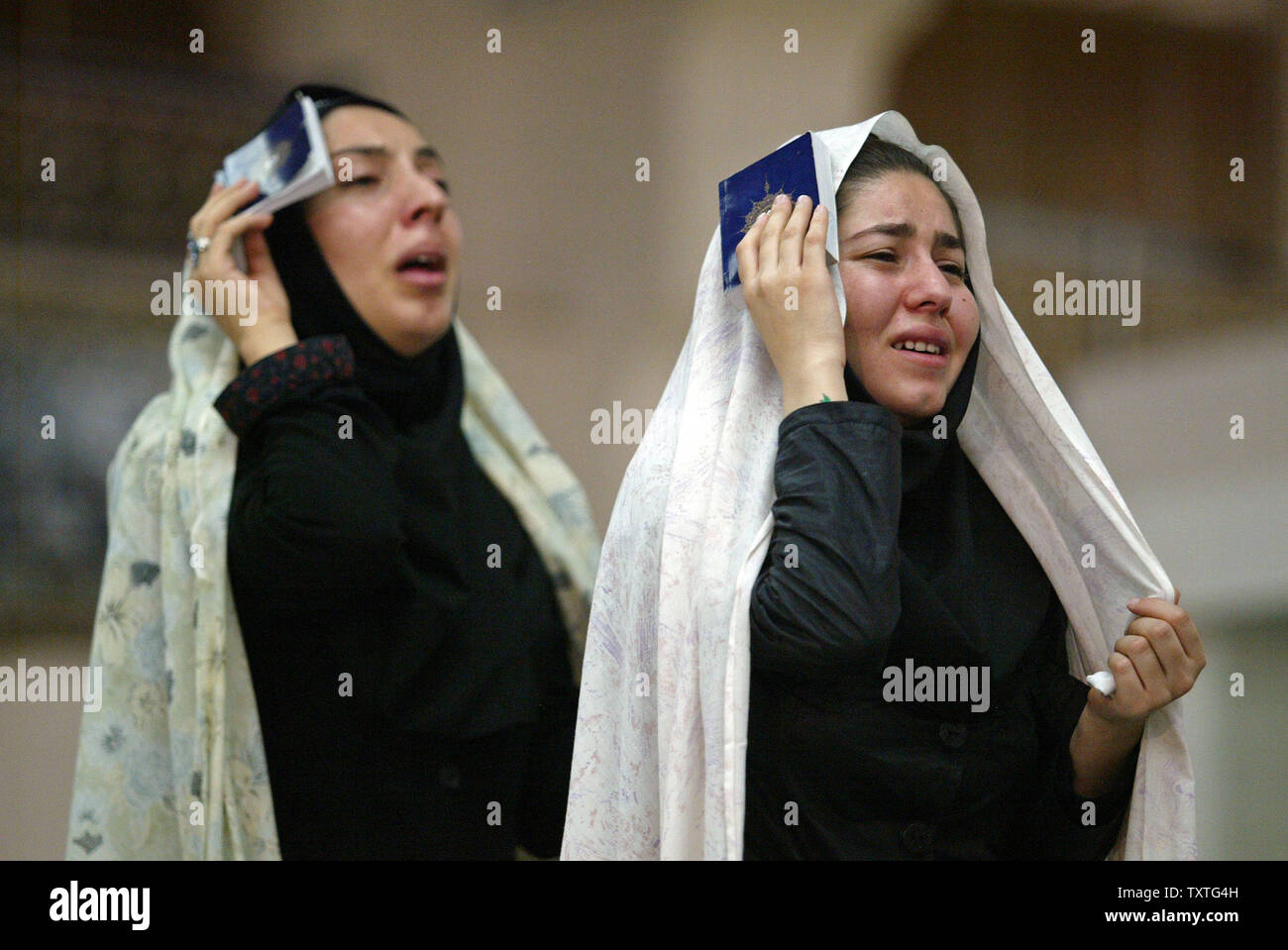 Iranian women cry as they hold copies of holy Koran on their heads ...