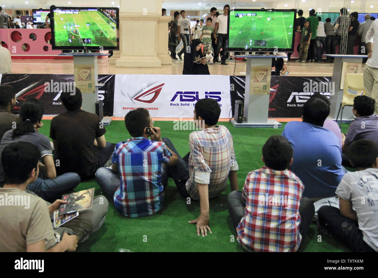 Iranian boys play and watch a soccer video game during the second ...
