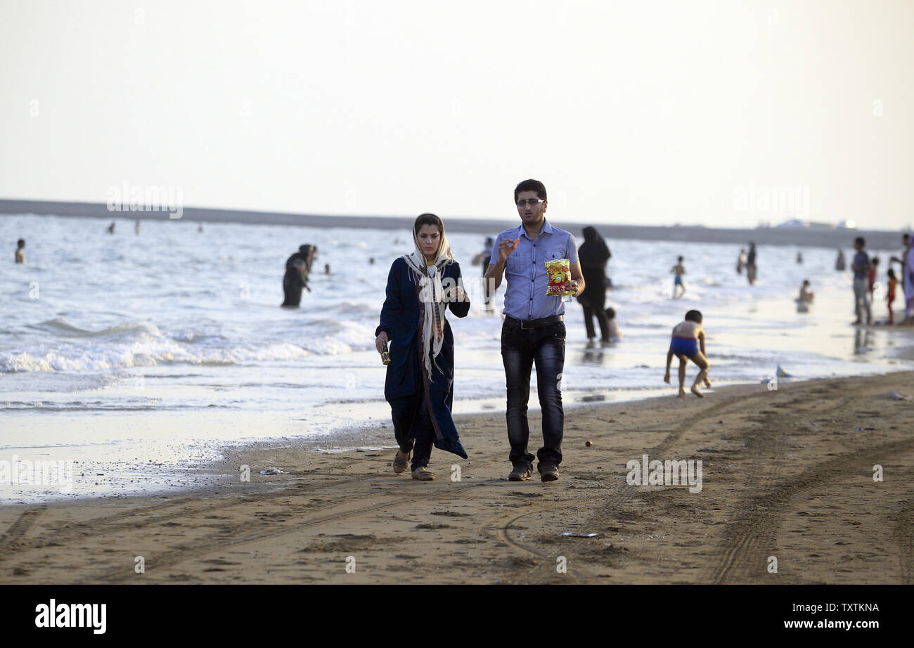 An Iranian couple walk on the beach of the Persian Gulf in Bandar Abbas ...