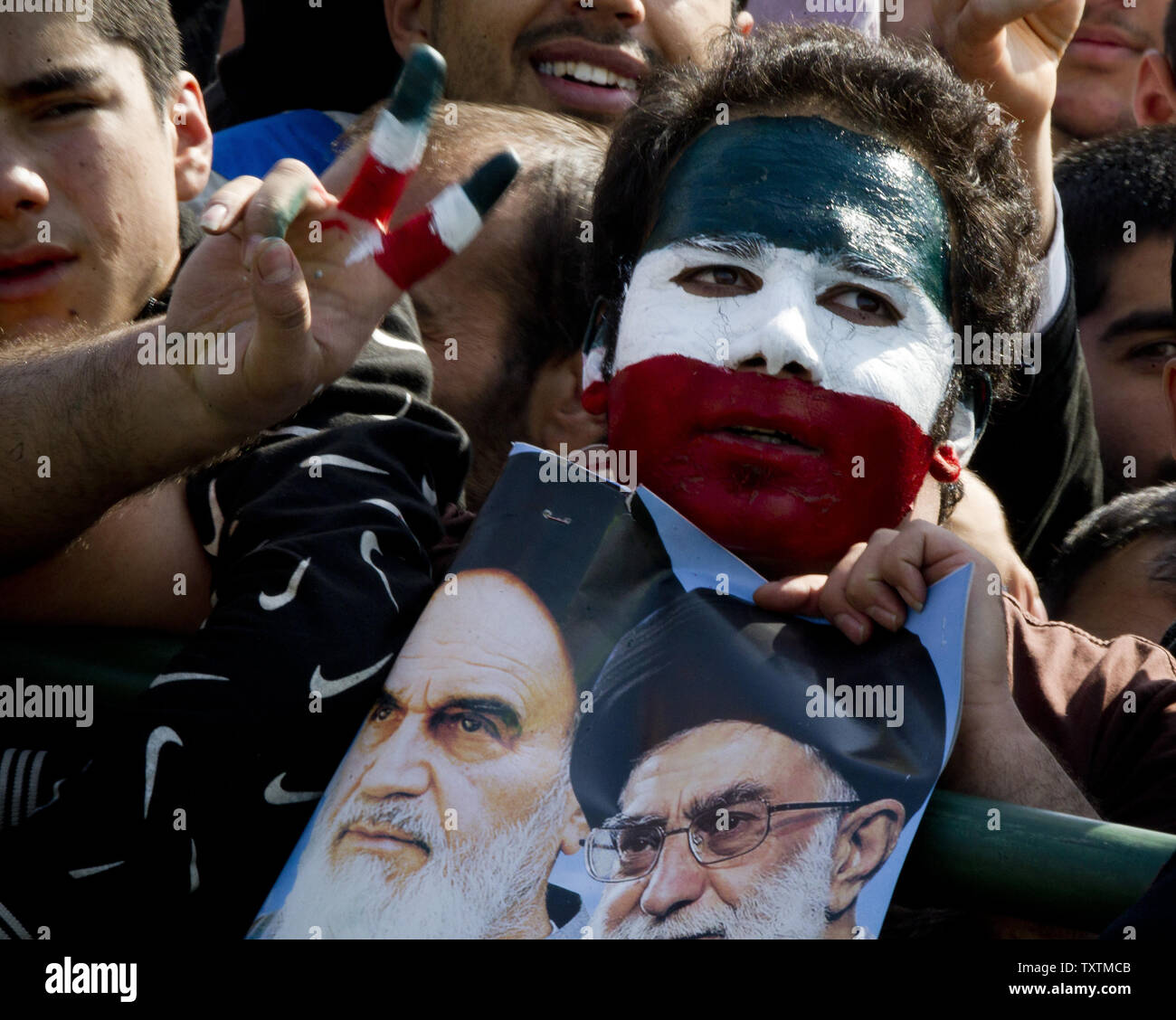 An Iranian man paints his face with the Iranian flag and holds a ...