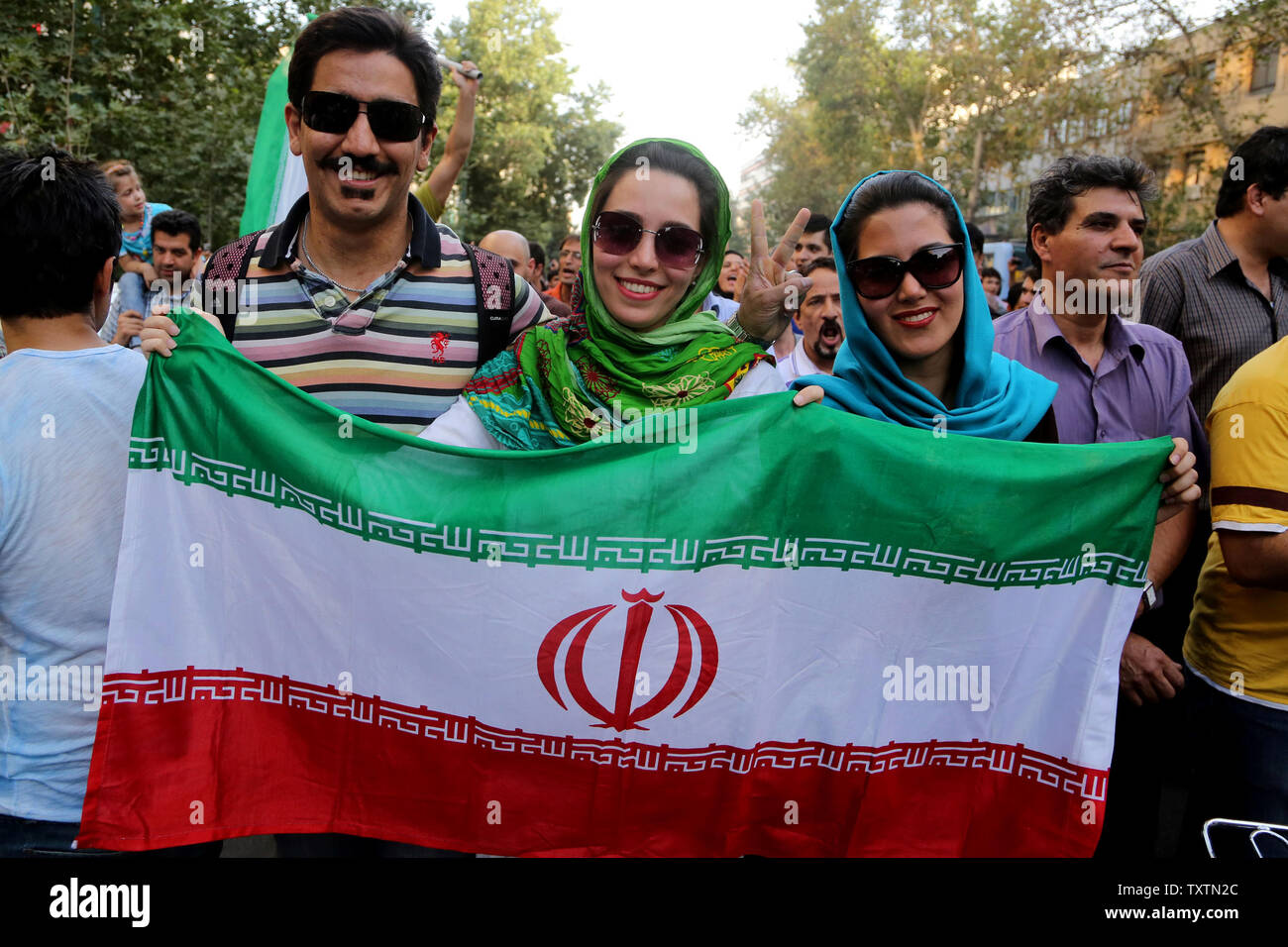 Iranian soccer fans flash the victory sign during a street celebration ...