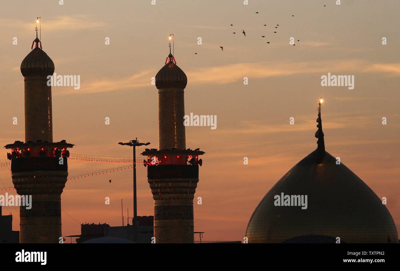 Sun sets behind the shrine to Imam Hussein during Ashura in Karbala ...