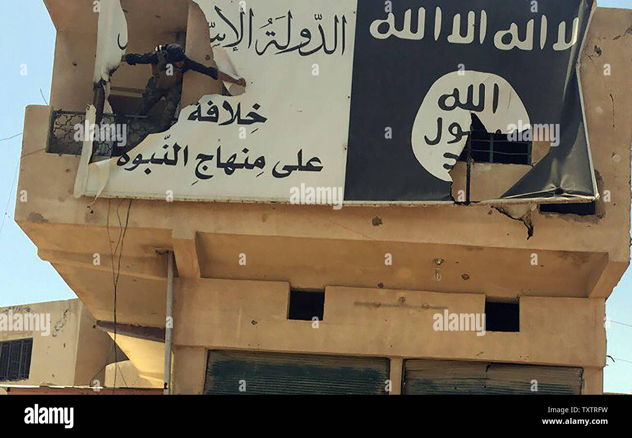 Iraqi soldier tearing a flag of the Islamic State group, from on the ...