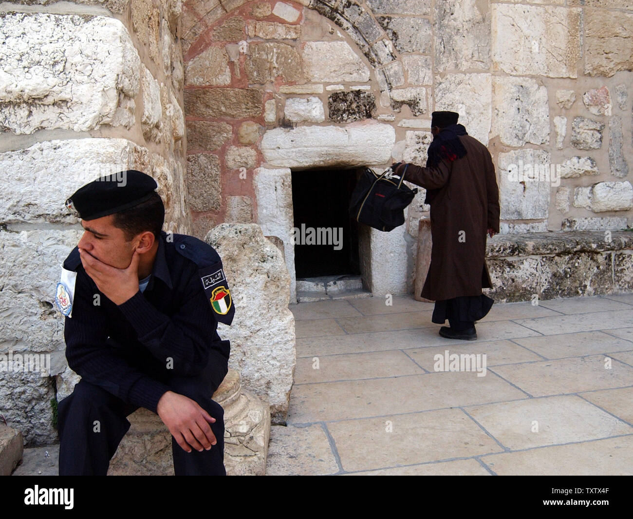 A Palestinian policeman sits outside the door to the Church of Nativity ...