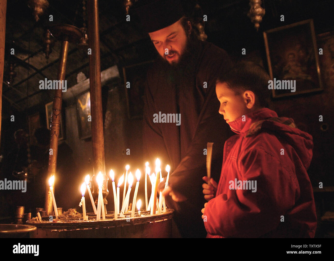 A priest lights candles in the grotto of the Church of Nativity, where ...