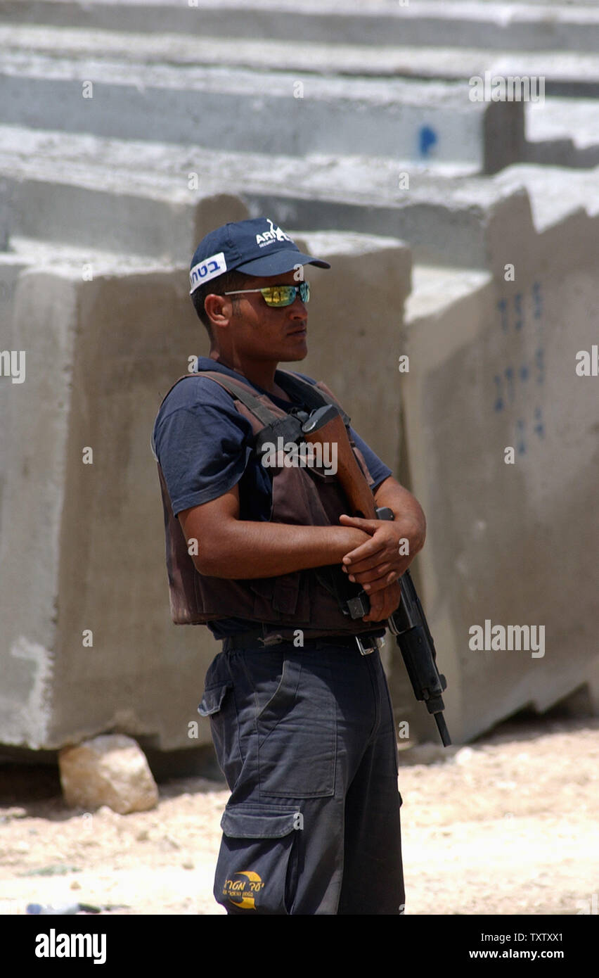 An Israeli security guard stands near 8 meter cement slabs that will be ...