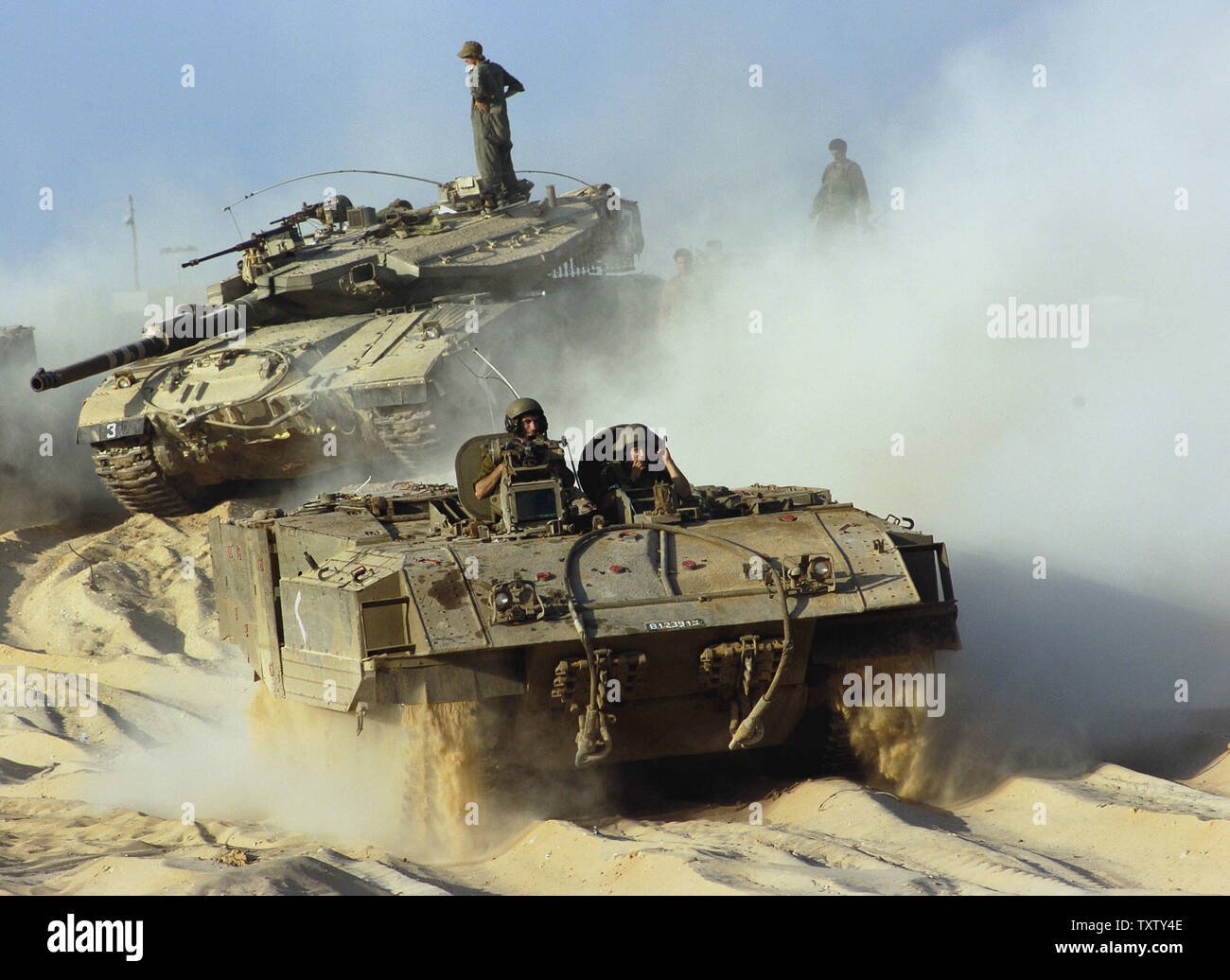 An Israeli armoured personnel carrier and tank prepare to enter ...