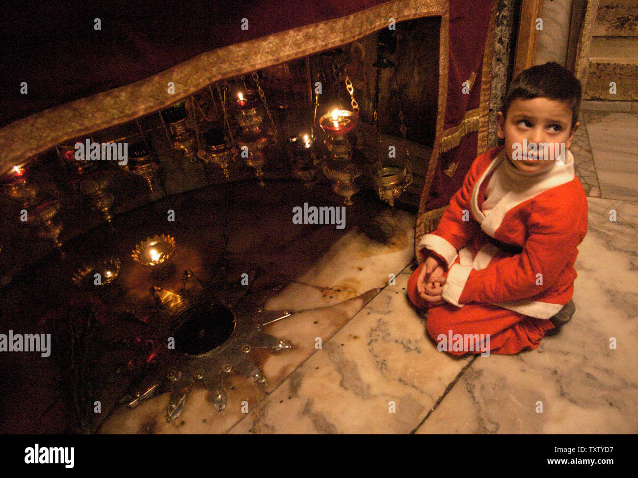 Michael Robie, 4 years, from Bet Jala, wears a Santa suit as he kneels ...