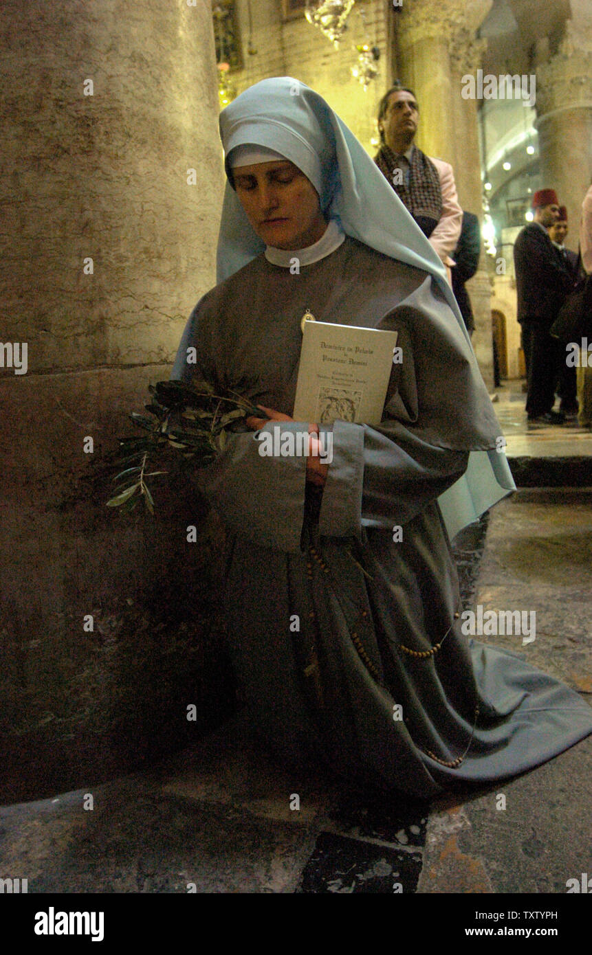 A nun holds an olive branch while praying on Palm Sunday in the Church ...