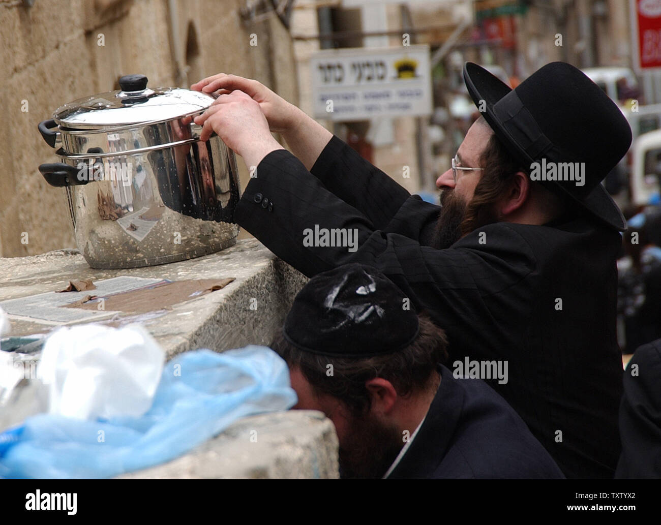 An Ultra-Orthodox Israeli Jew reaches for a pot to dip in boiling water ...