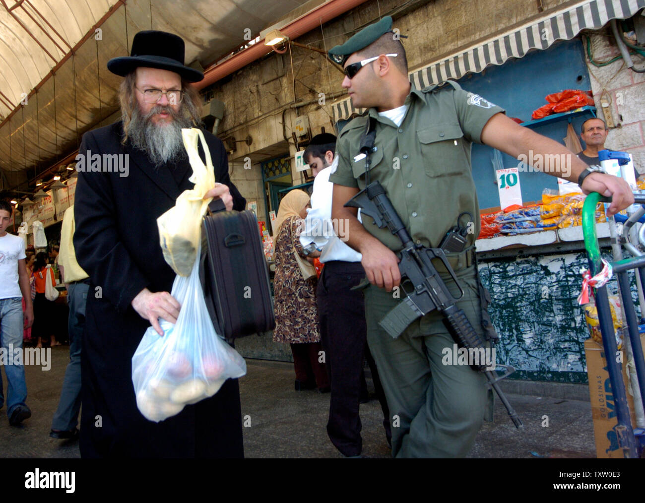 An ultra-Orthodox Jew walks past an Israeli border police guarding the ...