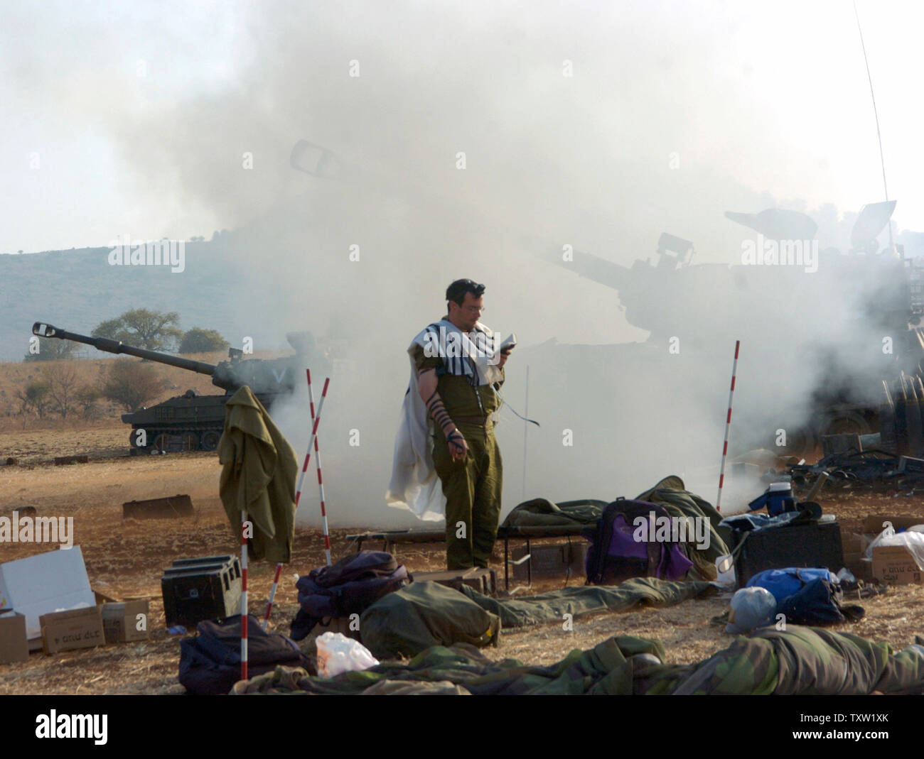 An Israeli soldier prays in the morning near a cannon in an artillery ...