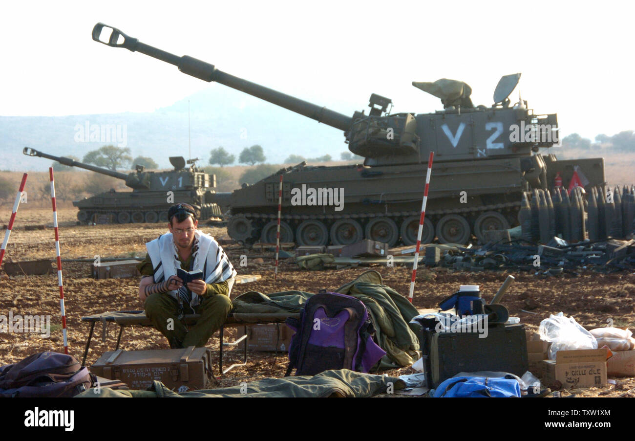 An Israeli soldier prays in the morning near a cannon in an artillery ...