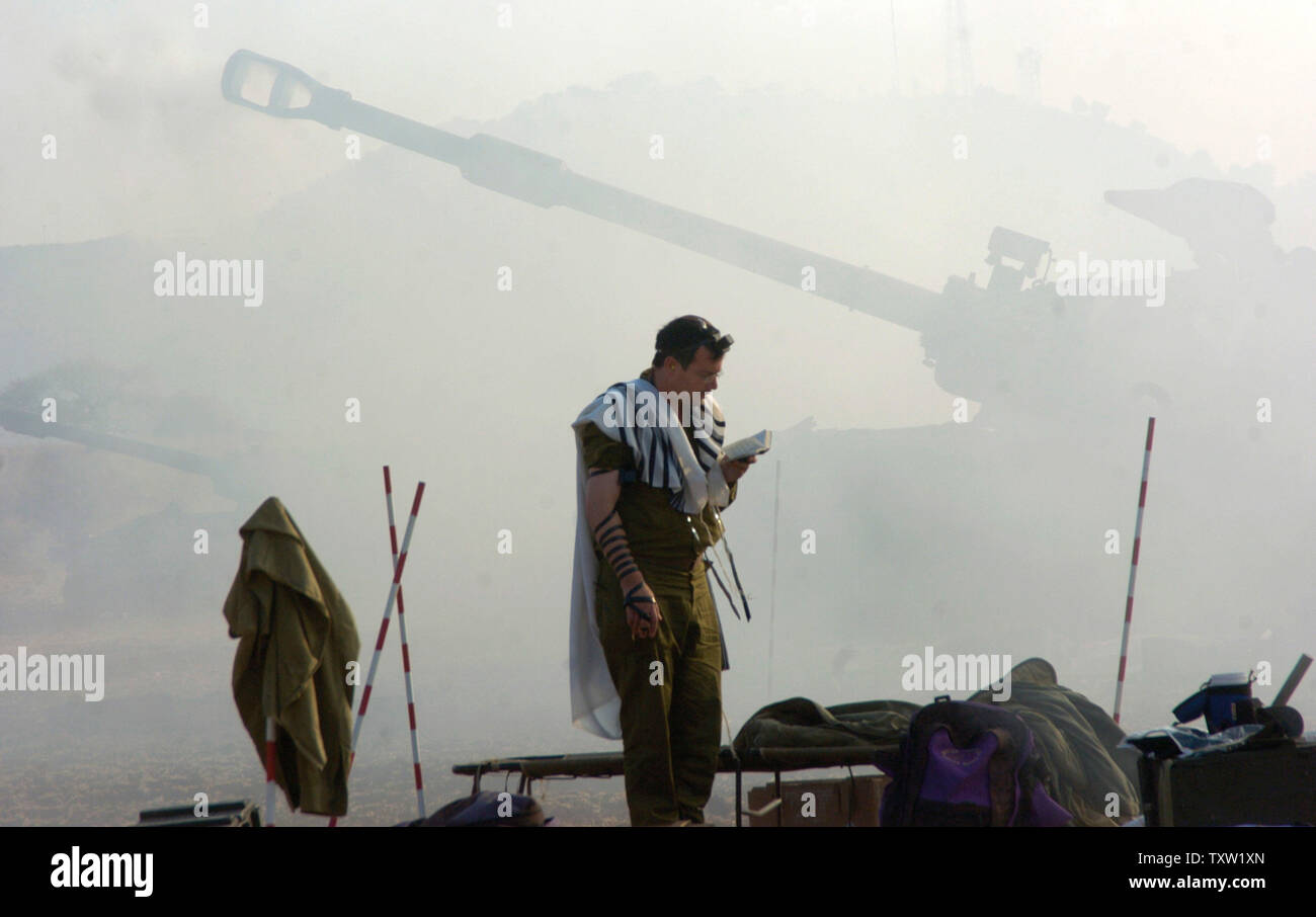 An Israeli soldier prays in the morning near a cannon in an artillery ...