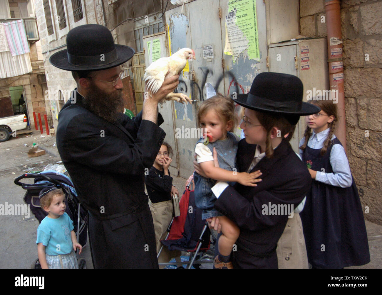 An Ultra-orthodox Israeli holds a chicken over his daughter's head ...