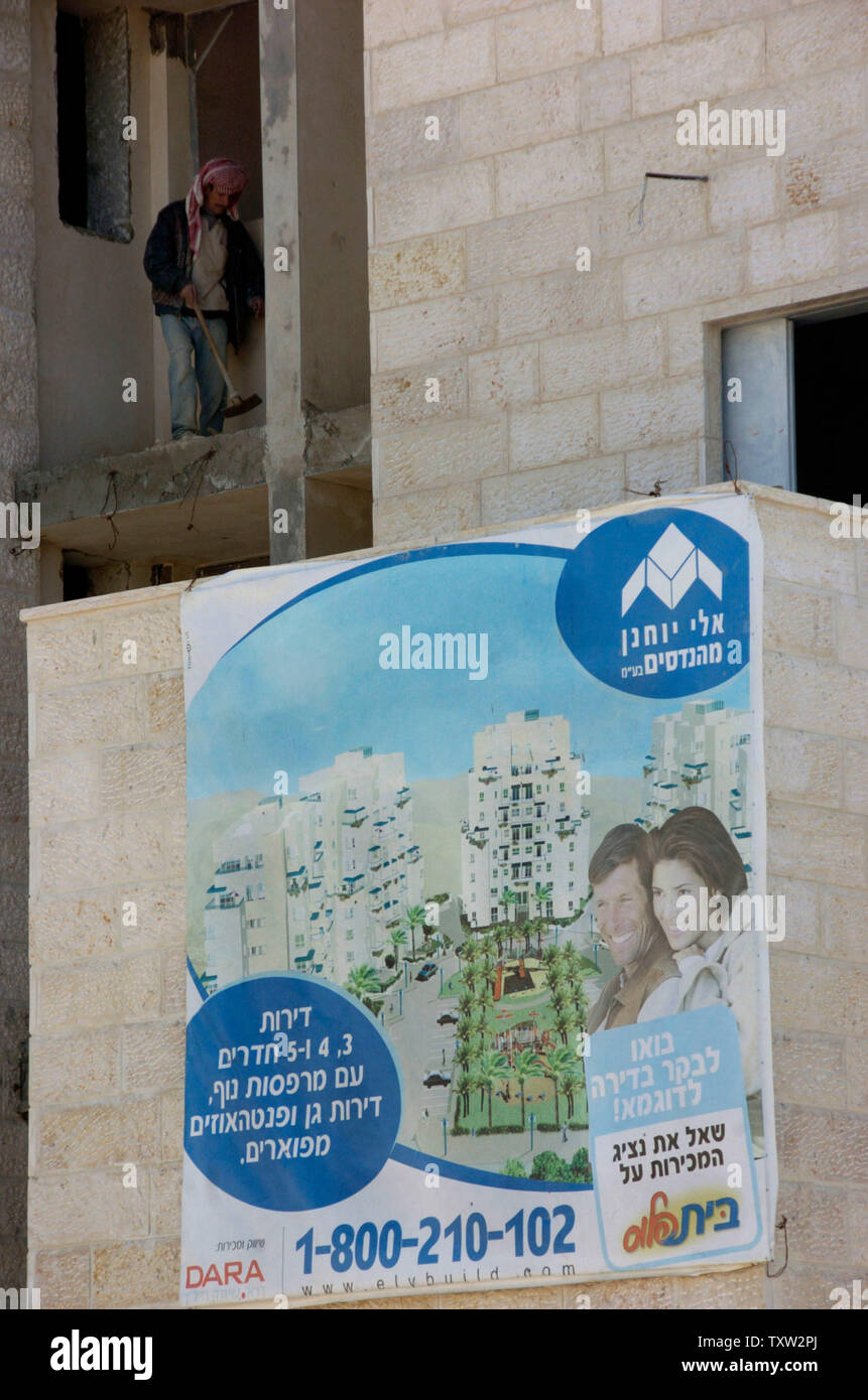 A Palestinian works above an poster advertising the sale of apartments ...