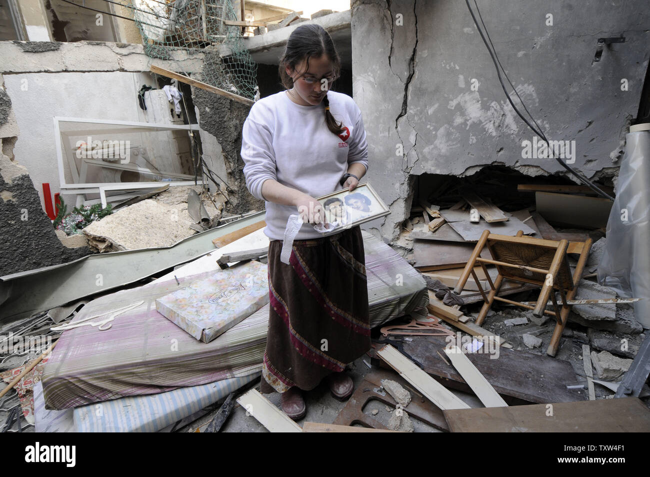 An Israeli volunteer clears debris from a house destroyed by a Kassam ...
