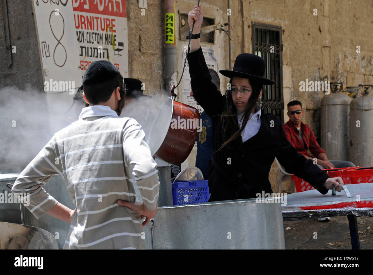 An Ultra-Orthodox Israeli dips cooking utensils into boiling water to ...