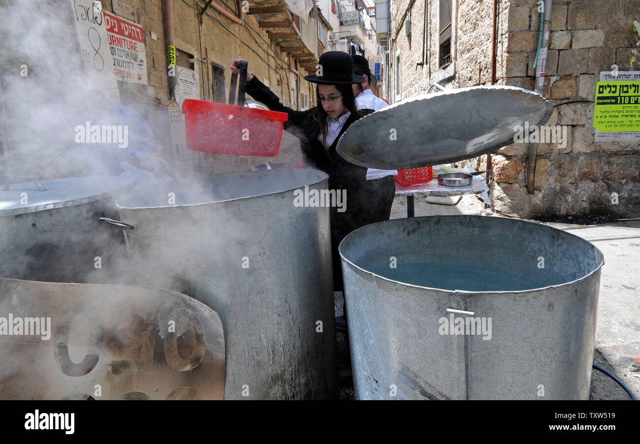 An Ultra-Orthodox Israeli dips cooking utensils into boiling water to ...