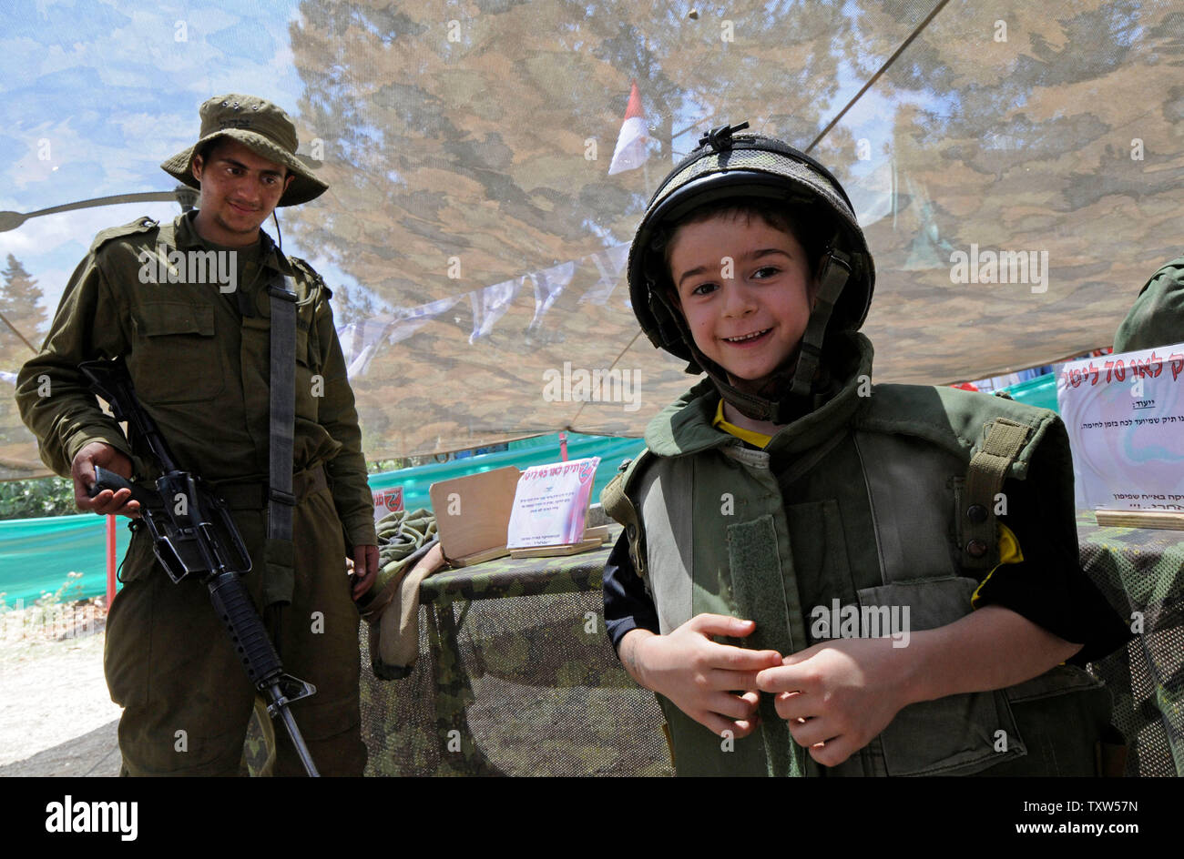 An Israeli soldier smiles at a child dressed in combat gear at a ...