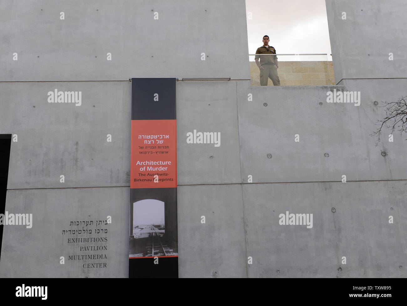 An Israeli soldier stands above a banner announcing an exhibition at ...