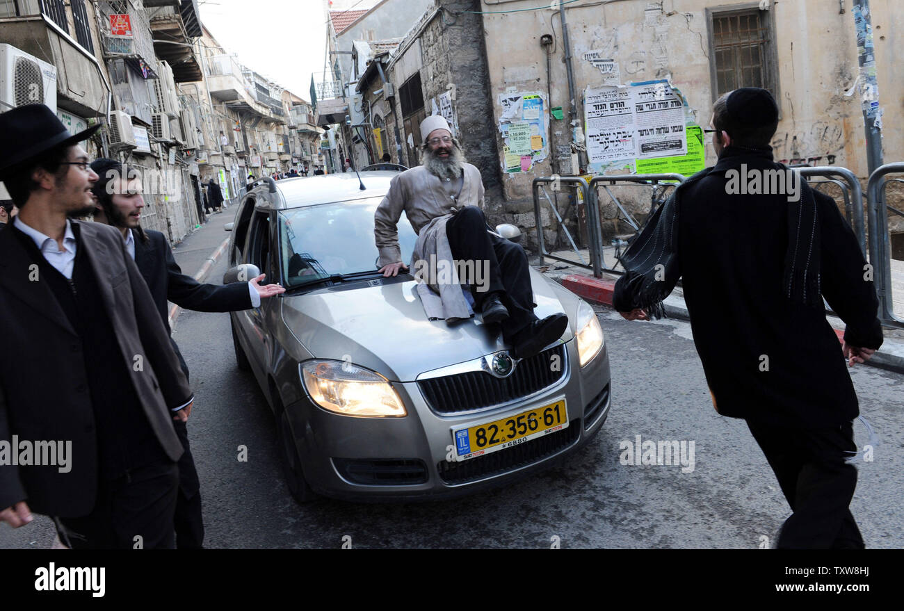 An Ultra-Orthodox Israeli rides on the hood of a car on the Jewish ...