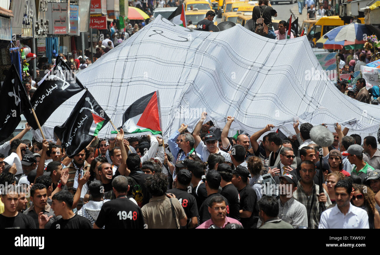 Palestinians carry a large traditional kafiyah at a rally commemorating ...