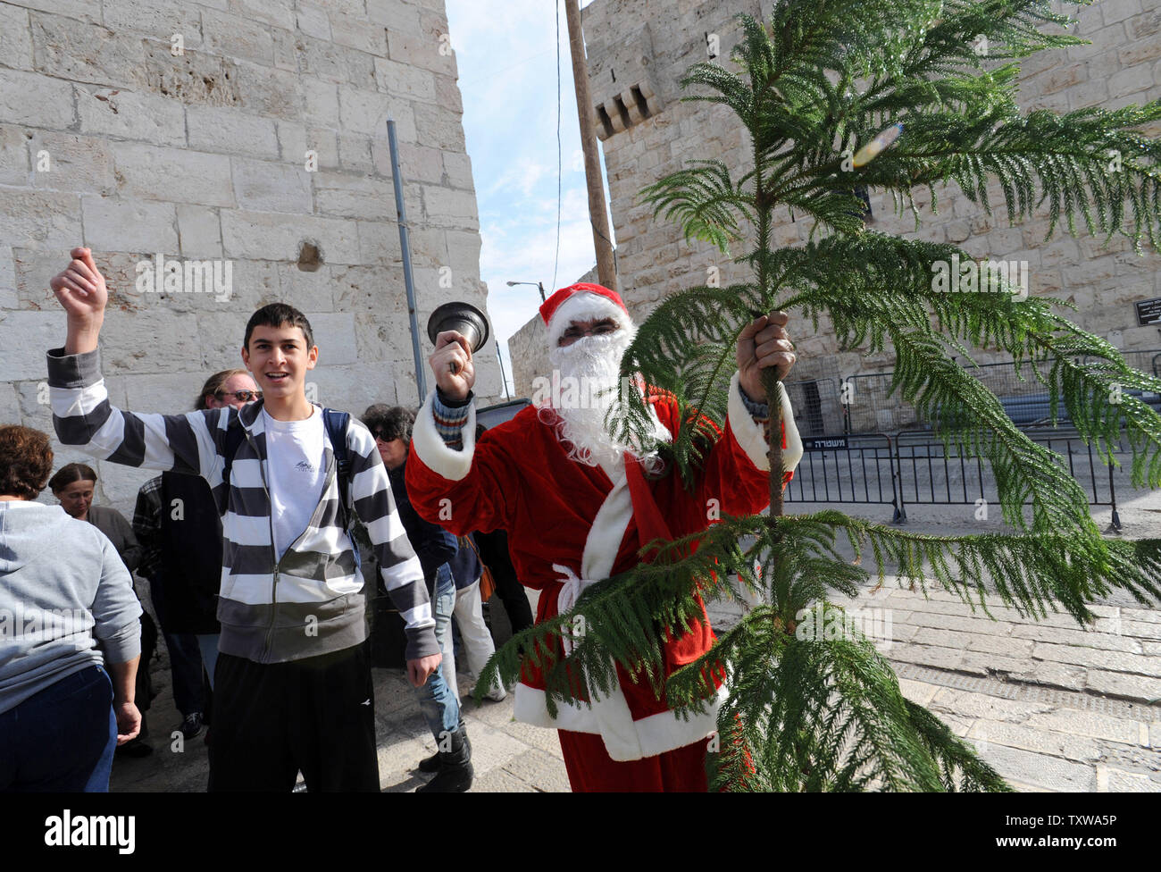 A Jewish youth pretends to ring a bell with a Palestinian Santa Claus ...