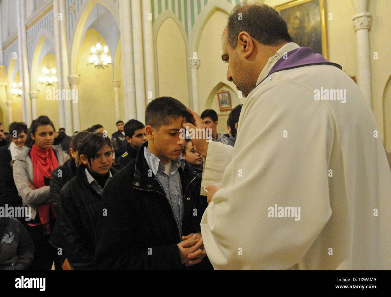 A Catholic priest uses ashes to make the sign of a cross on the ...