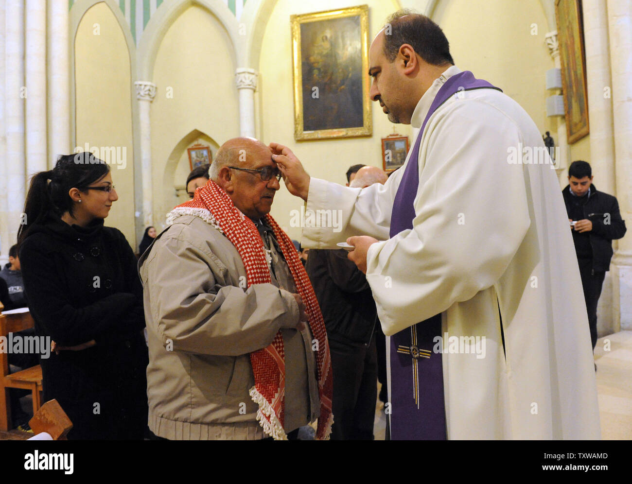 A Catholic priest uses ashes to make the sign of a cross on the ...