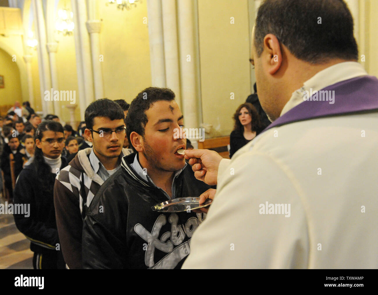 A Catholic priest serves Holy Communion to a Palestinian with ashes on ...