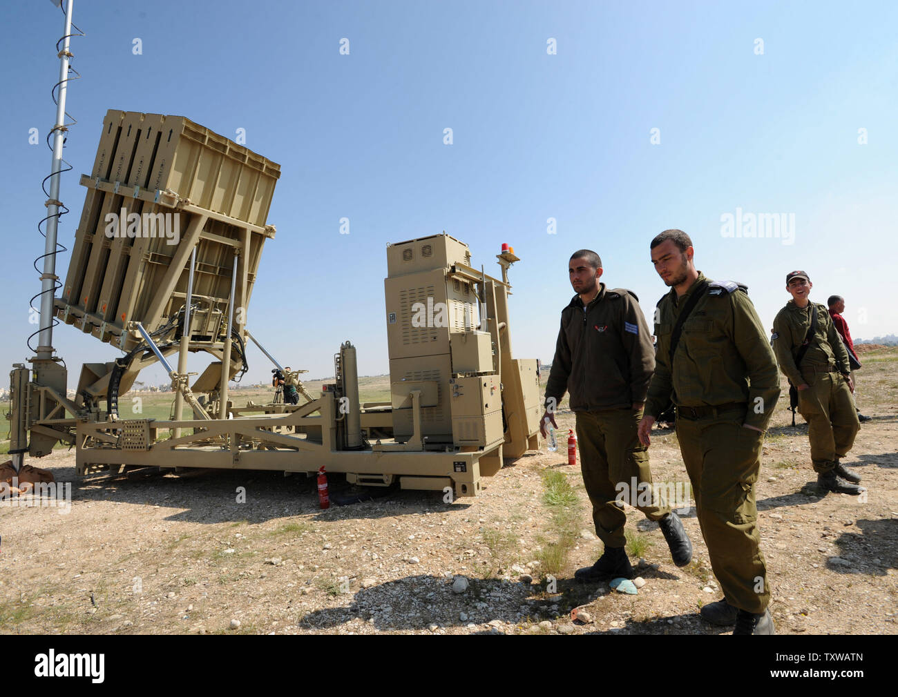 Israeli soldiers walk near the Iron Dome, a new anti-rocket system ...